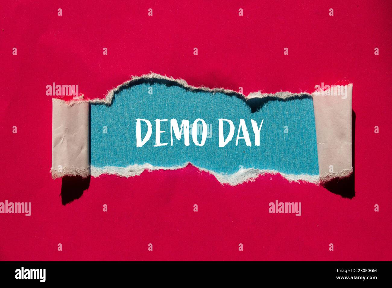 Demo day words written on ripped red paper with blue background ...