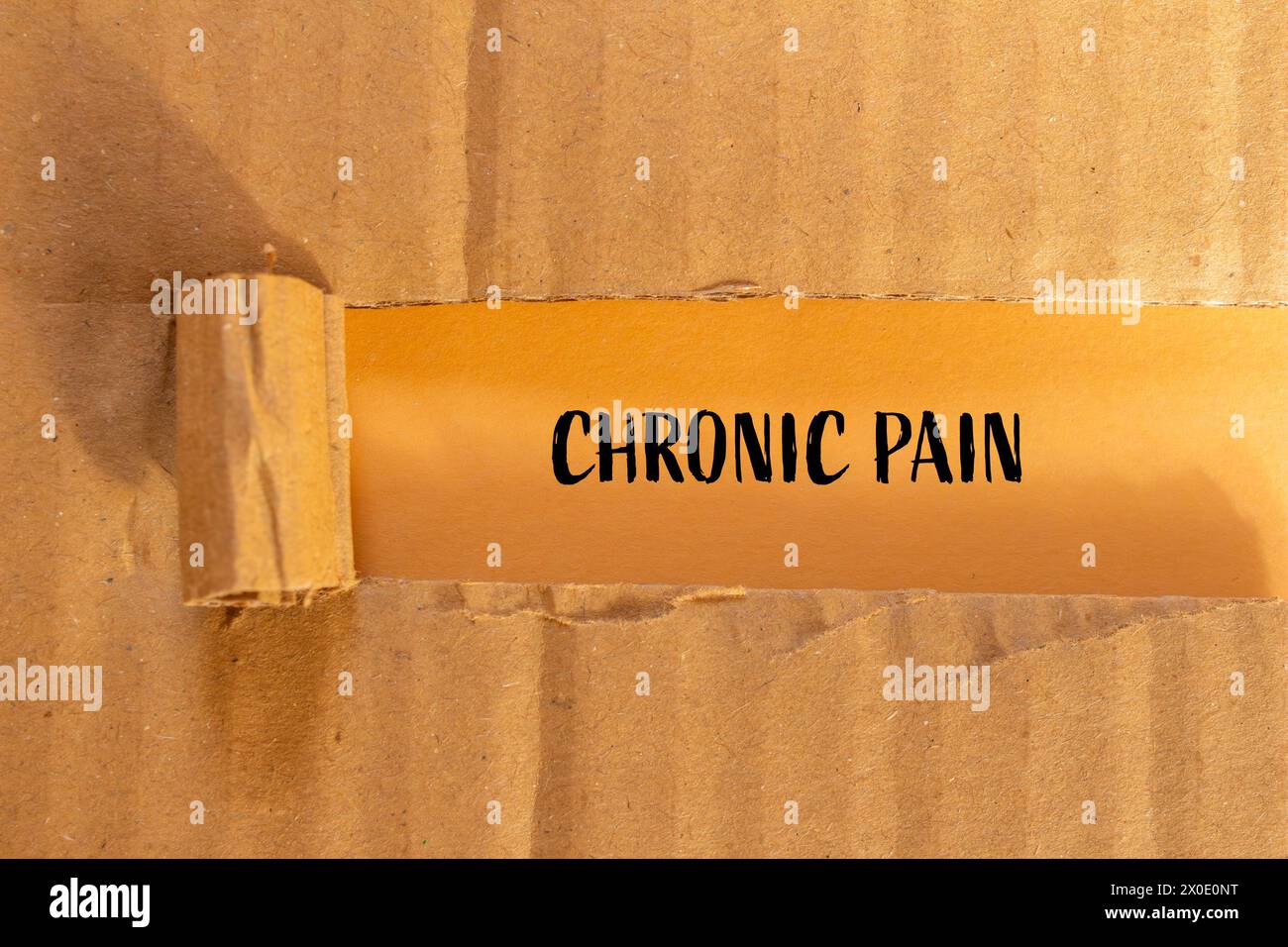 Chronic pain words written on ripped cardboard paper with orange ...