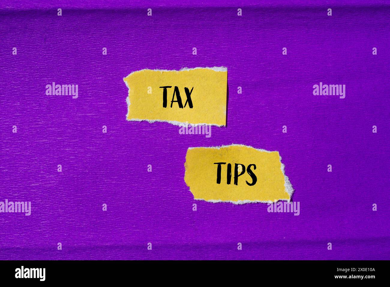 Tax tips words written on ripped yellow paper pieces with purple ...