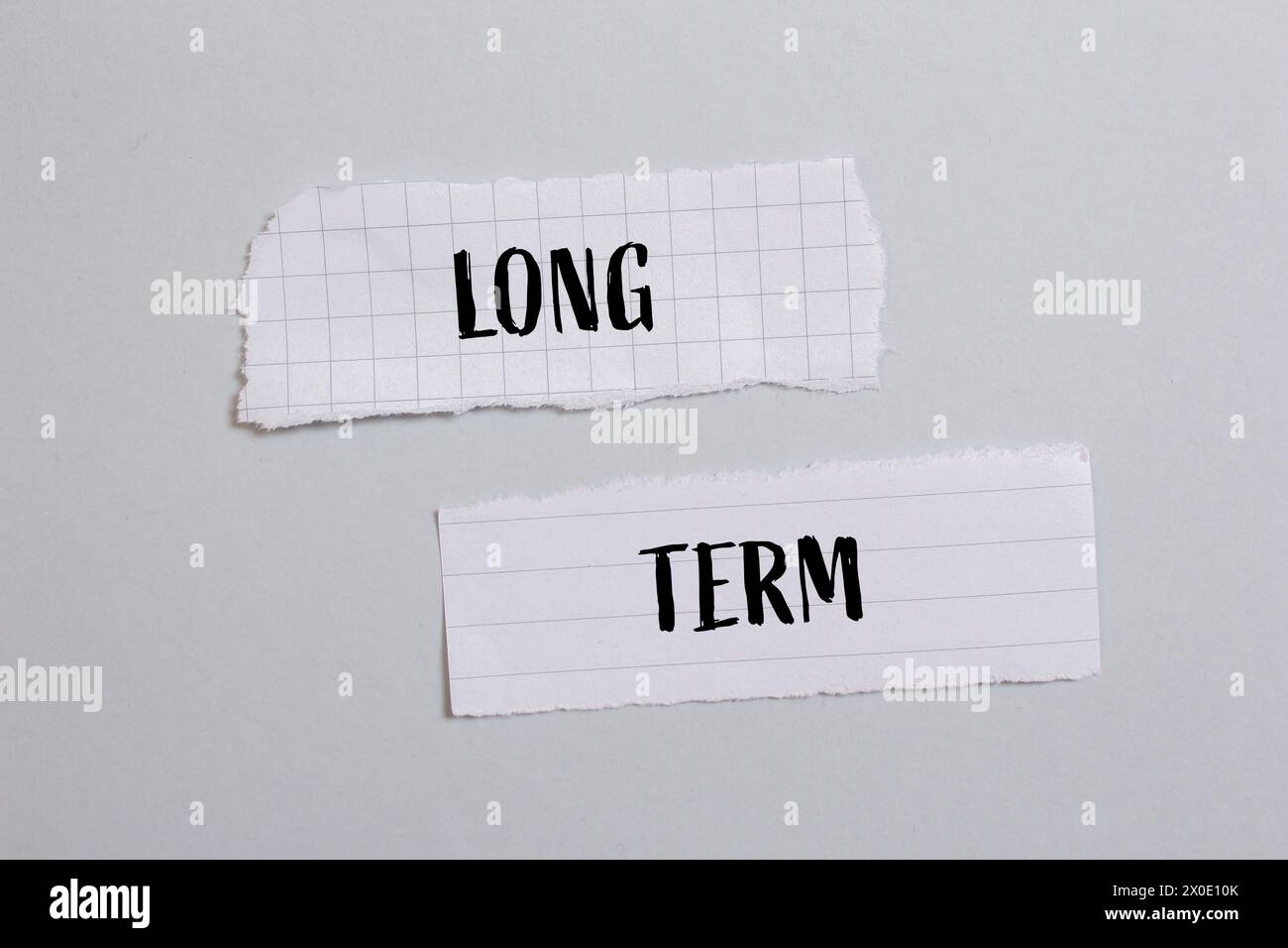 Long term words written on ripped paper pieces with gray background ...