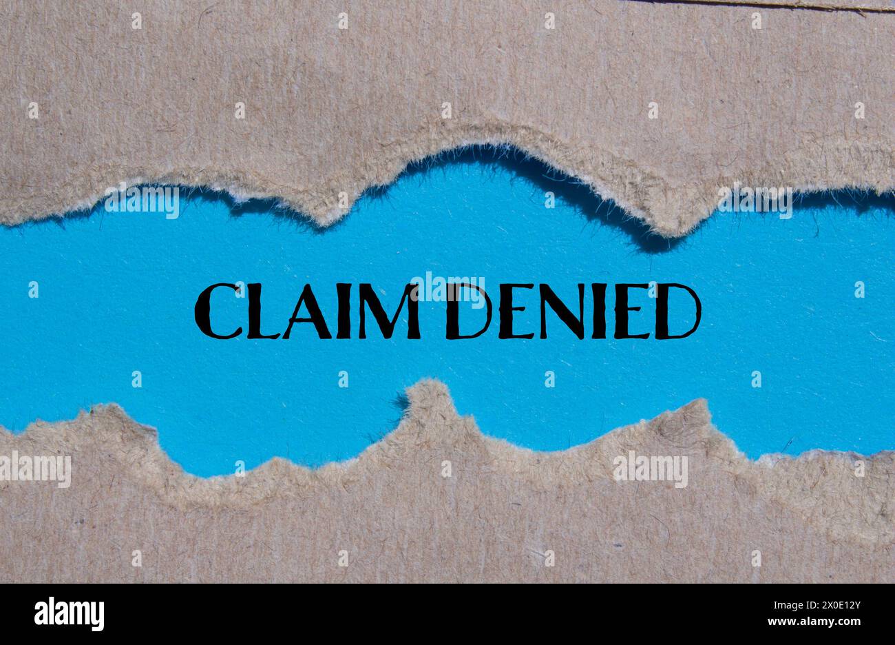 Claim denied words written on ripped paper with blue background ...