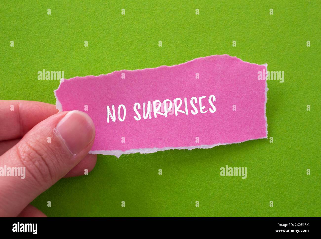 No surprises words written on ripped pink paper with green background ...