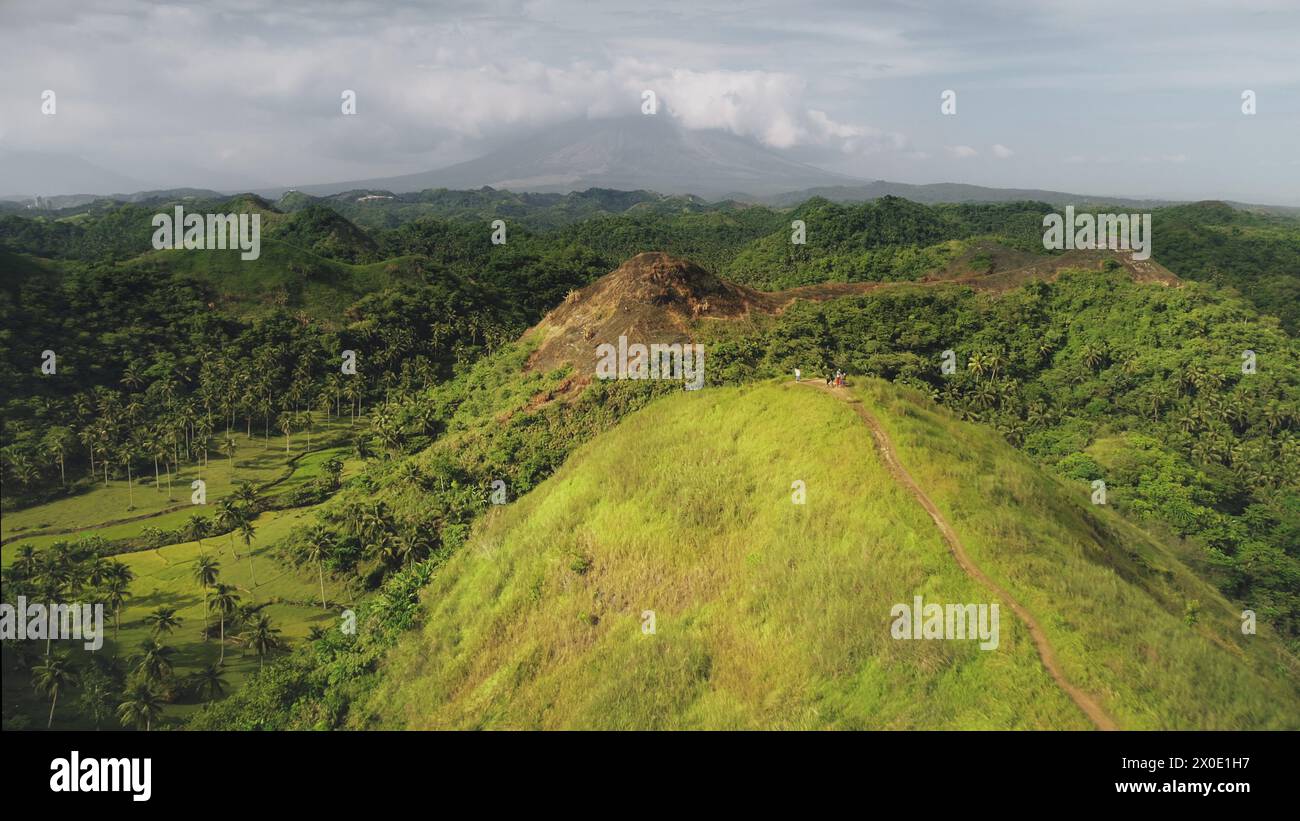 Aerial tourist hiking hill top: green grass mountain peak with ...