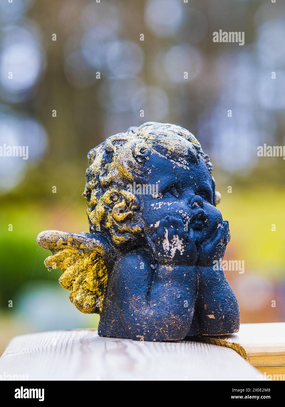 A weathered blue angel statue with golden wings. The background ...