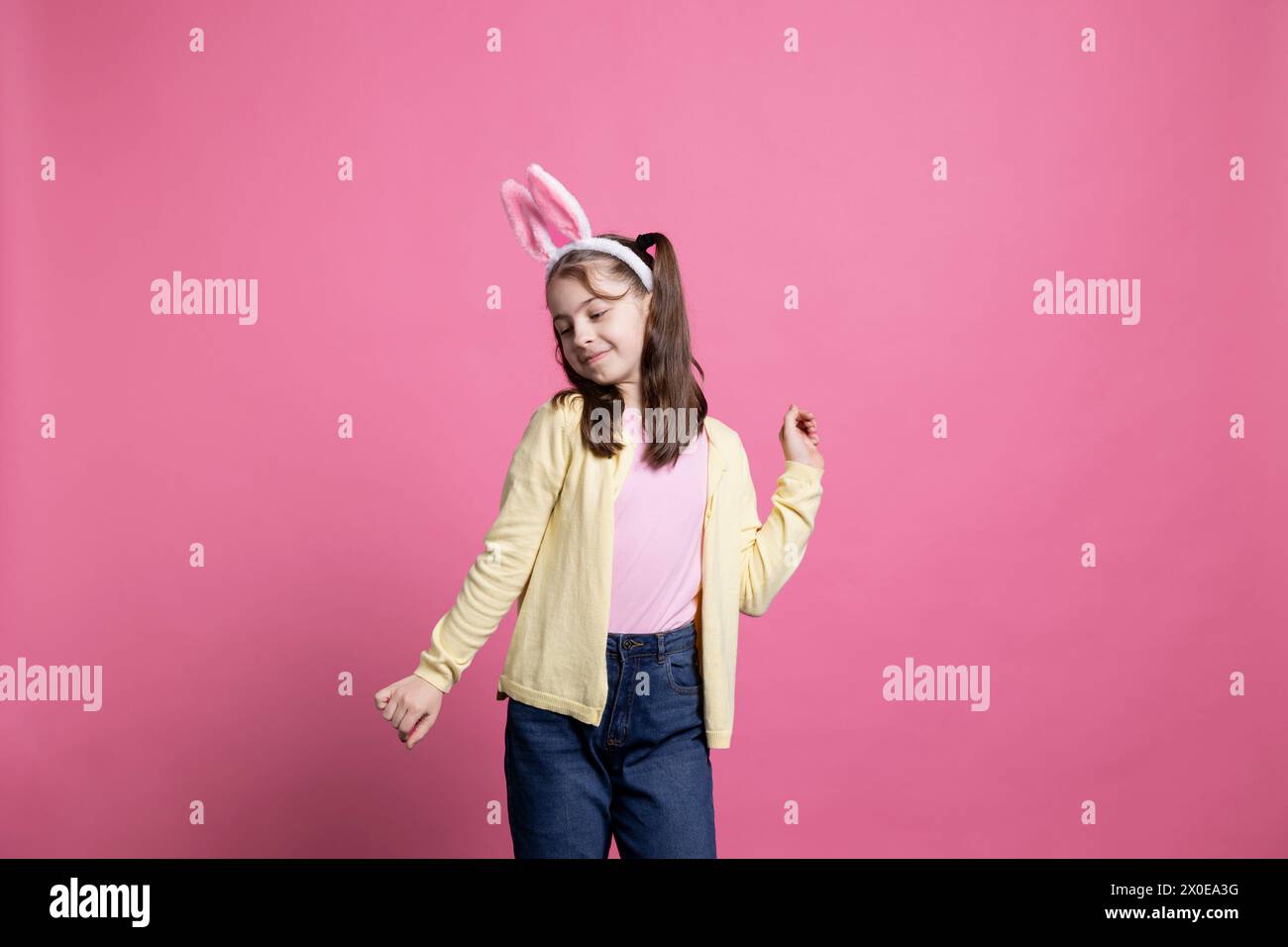 Happy cheery junior dancing around in the studio with fluffy bunny ears ...