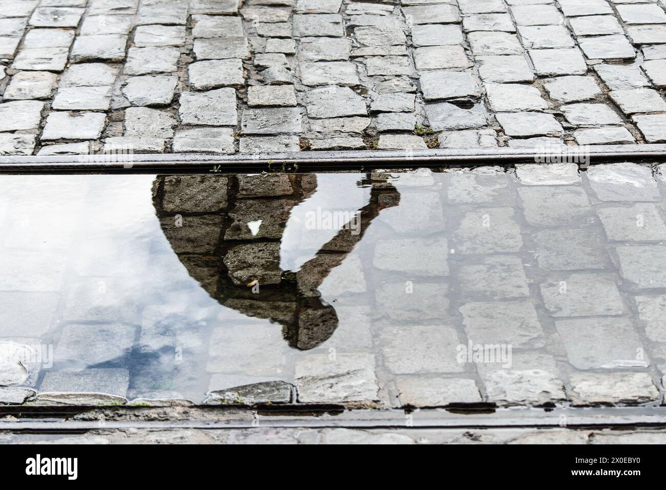 Reflection of person and bicycle in a puddle of rainwater in the river ...