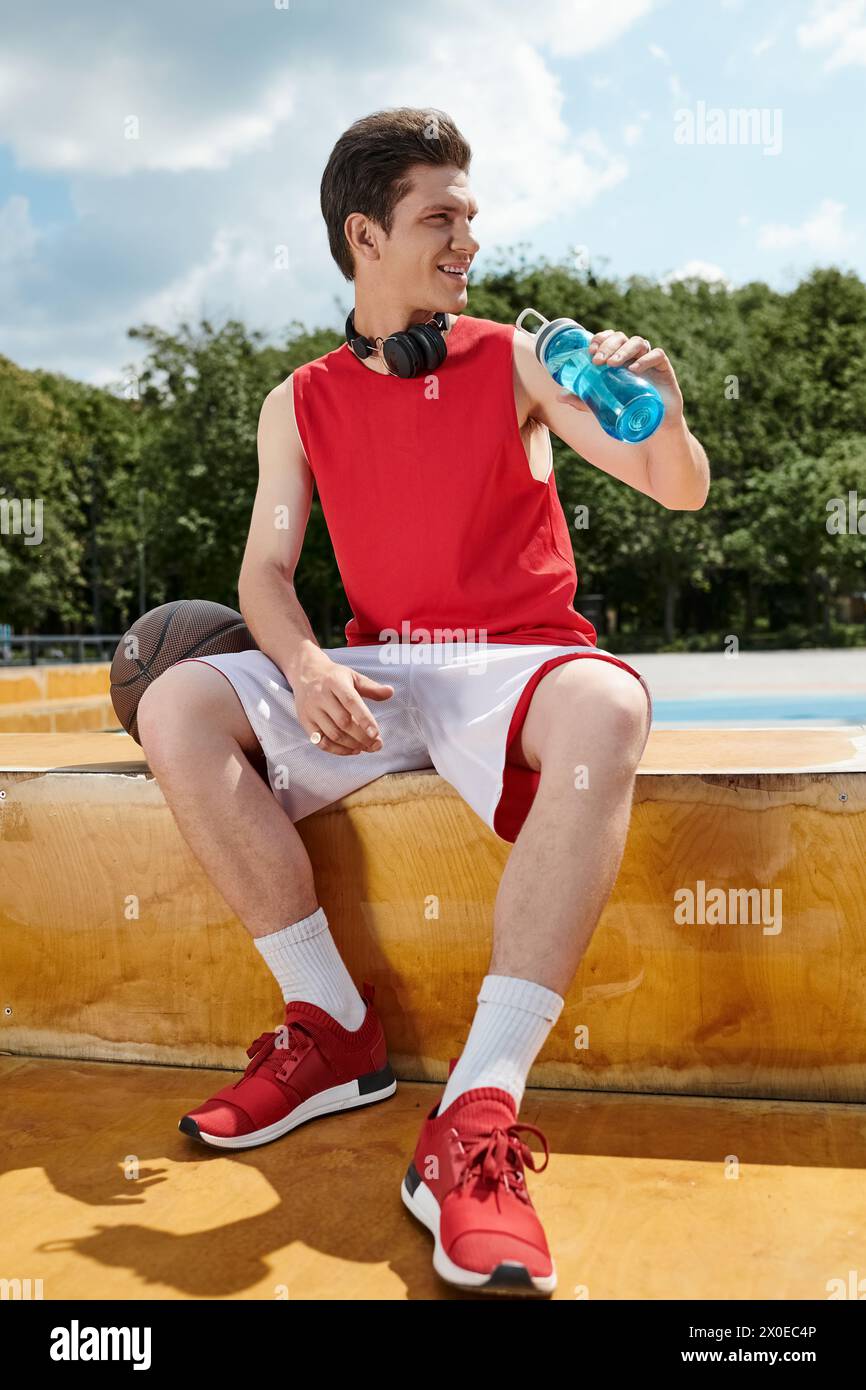 A man sitting on a ledge, taking a break to hydrate with a water bottle ...