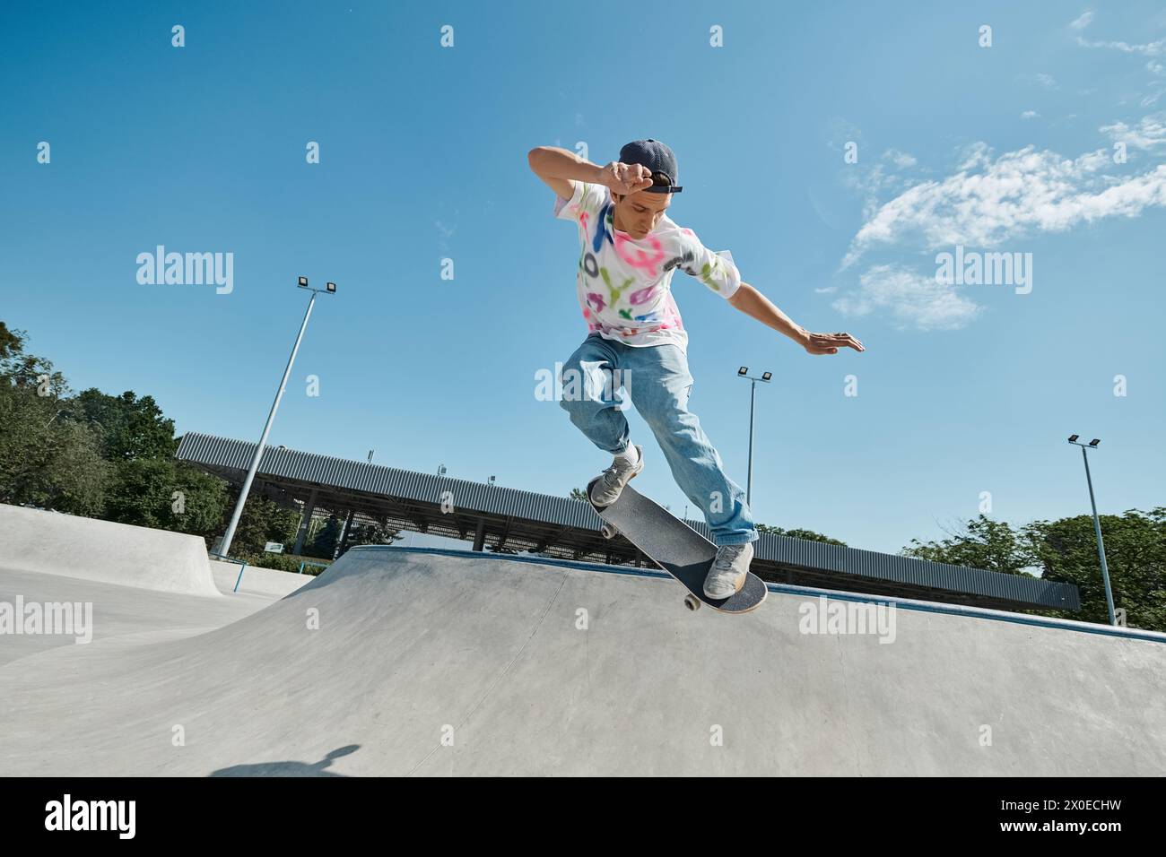 A young man confidently skateboards down the side of a ramp in a sunny ...