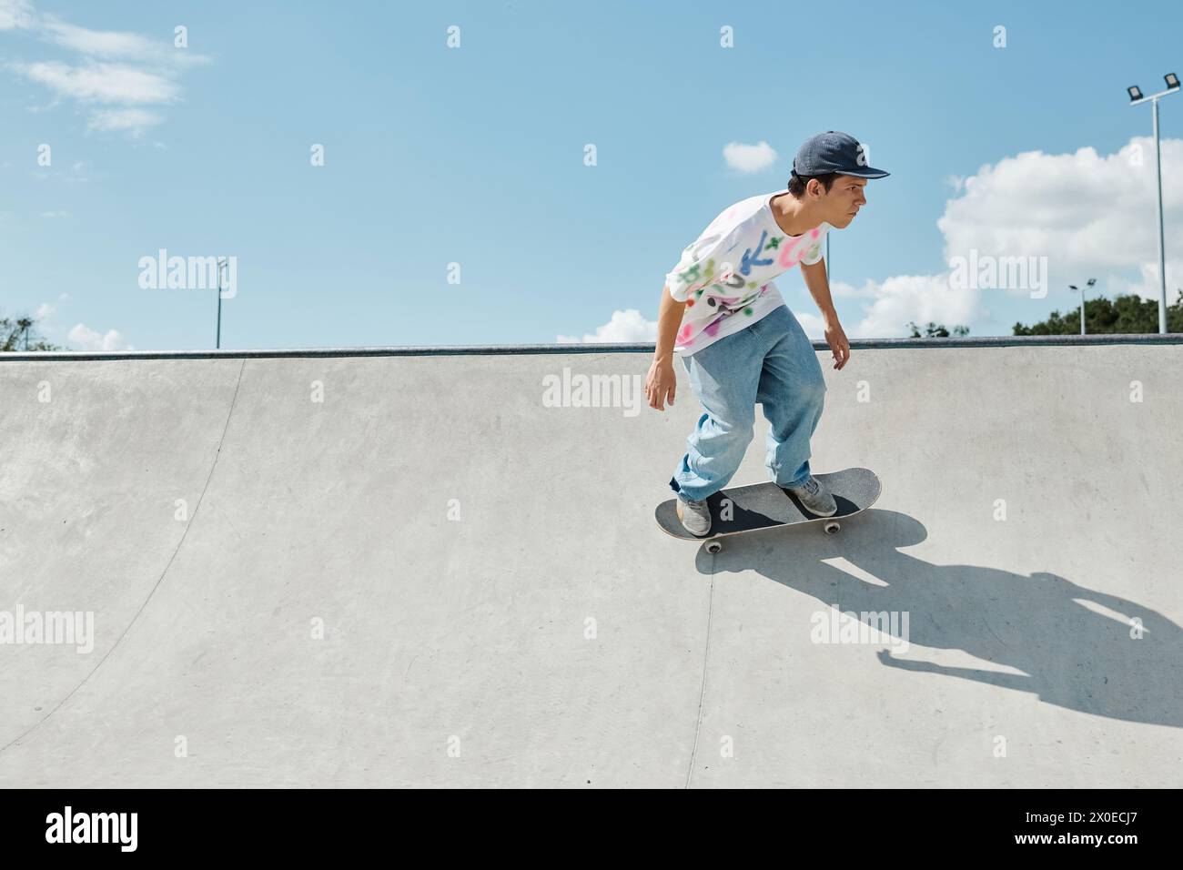A young man confidently rides a skateboard up a steep ramp at an ...