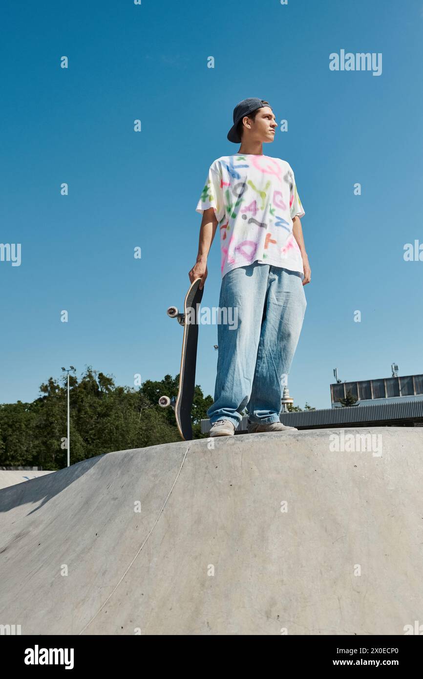 A young skater boy confidently stands on top of a skateboard ramp ...