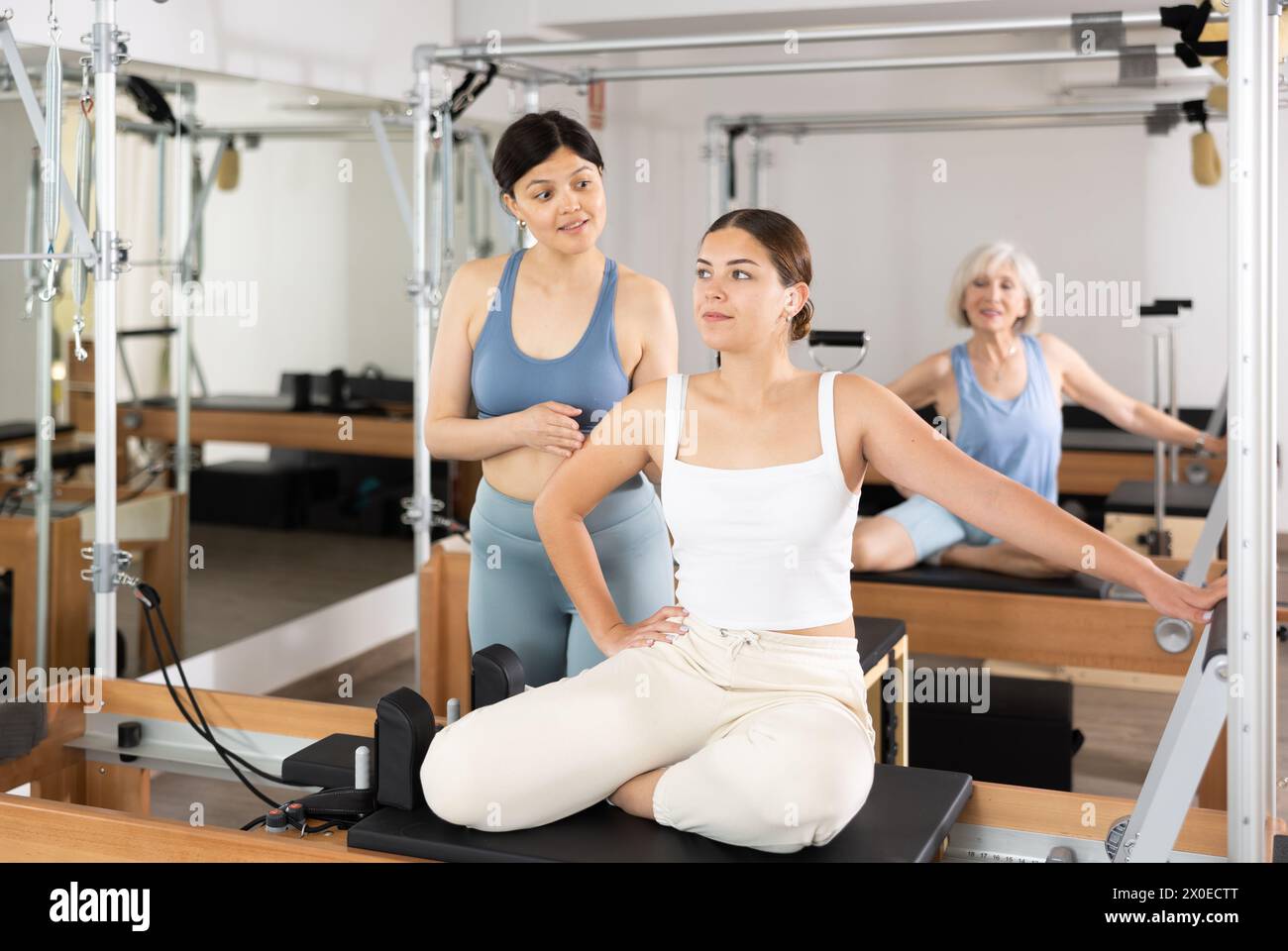 Woman doing pilates in fitness studio with female personal trainer ...