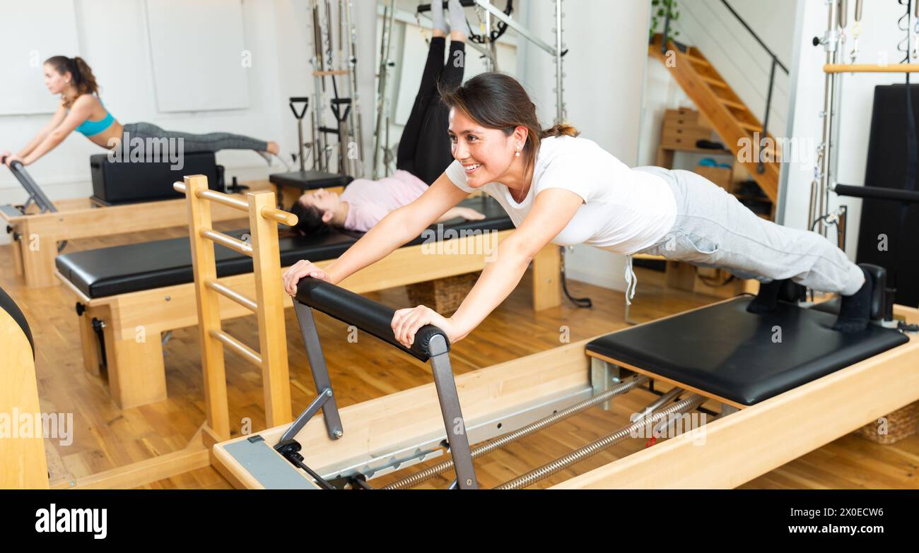 Sportswoman stretching body on pilates chair while doing forward bends ...
