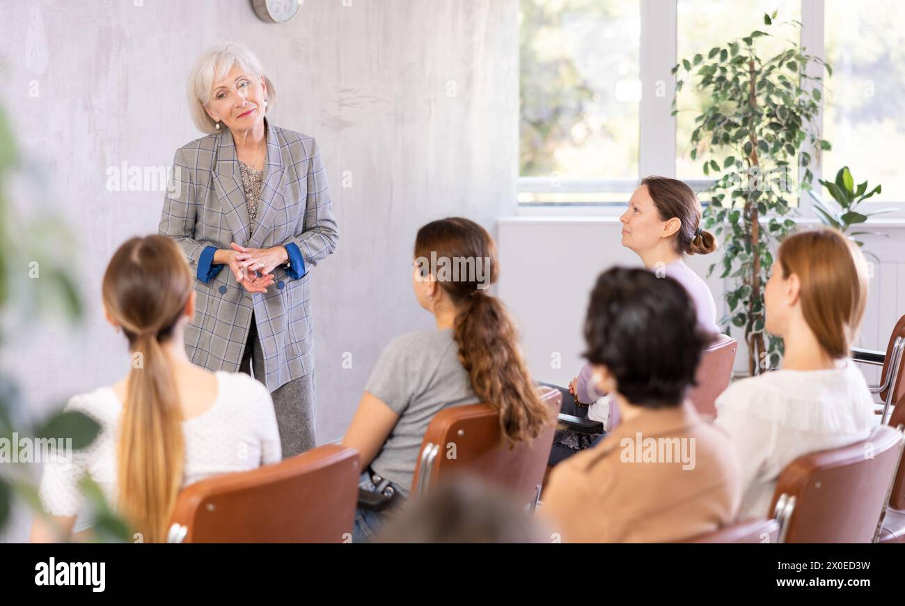 Positive elderly woman giving lecture to female group Stock Photo - Alamy