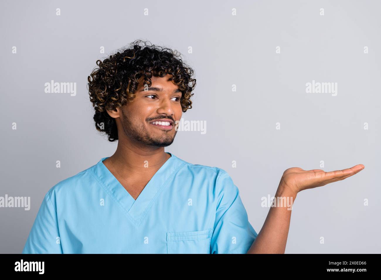Photo of positive doctor guy look hold hand advertising isolated grey ...