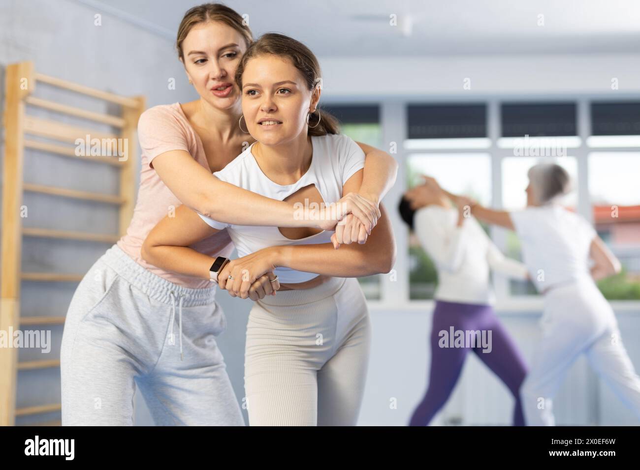 Woman and girl in gym perform basic elements of krav maga self-defense ...