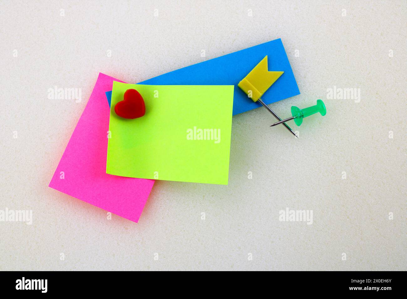 Heart shaped thumbtack holding notes along with two others of different ...