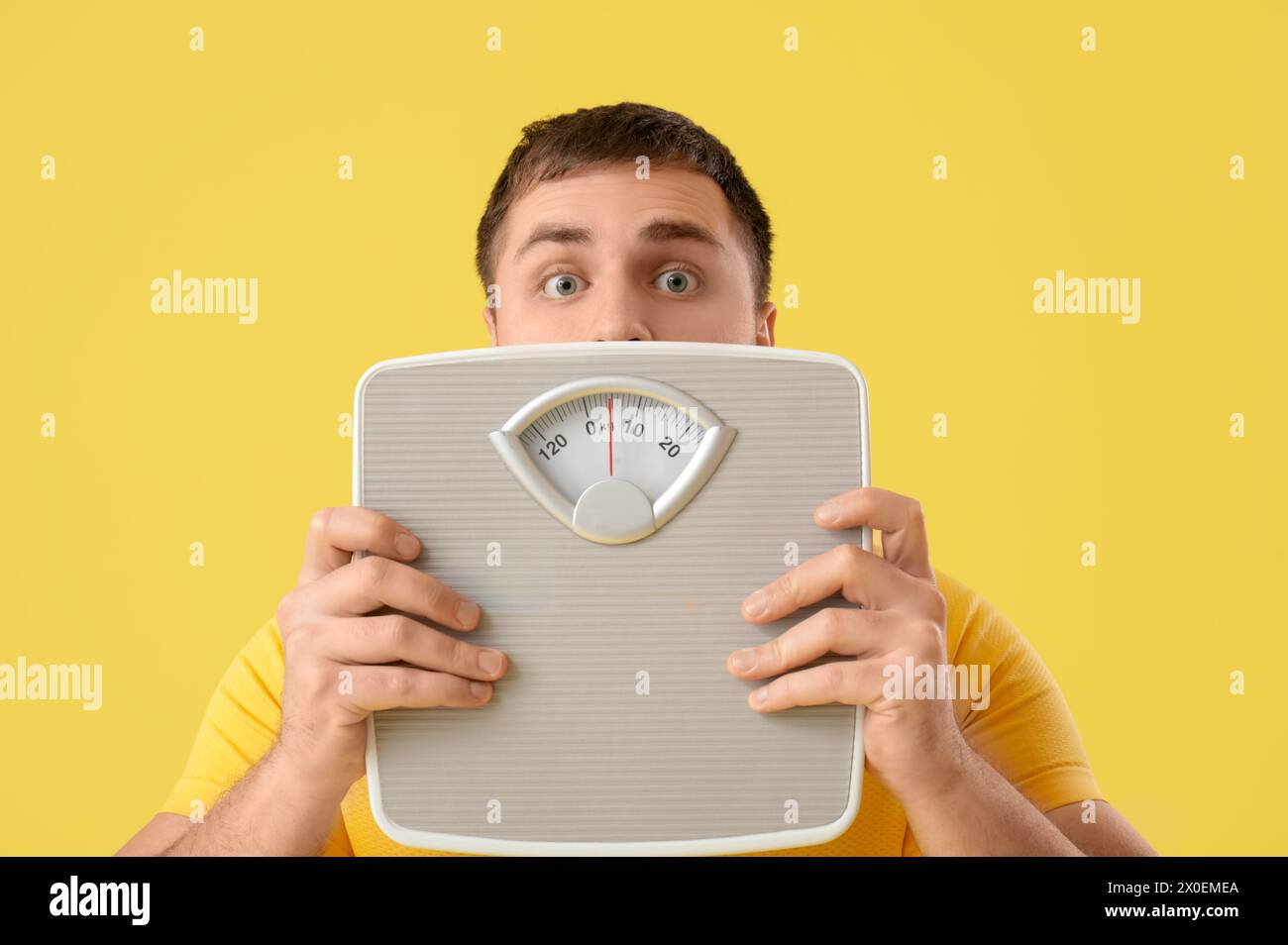 Shocked young man with scales on yellow background, closeup. Weight ...