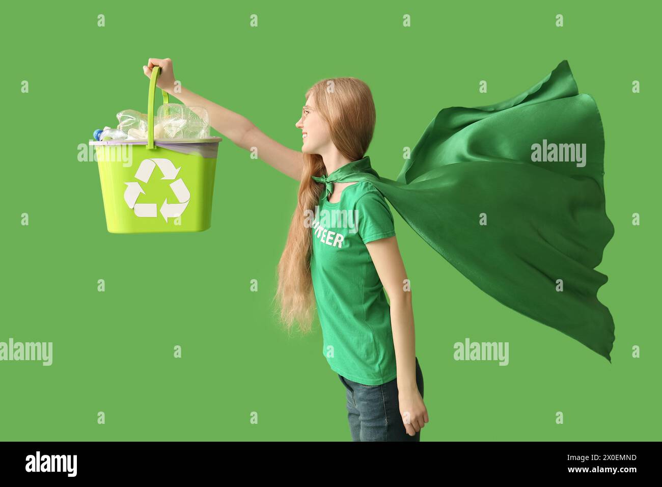 Female volunteer in superhero cape holding recycle bin with plastic on ...