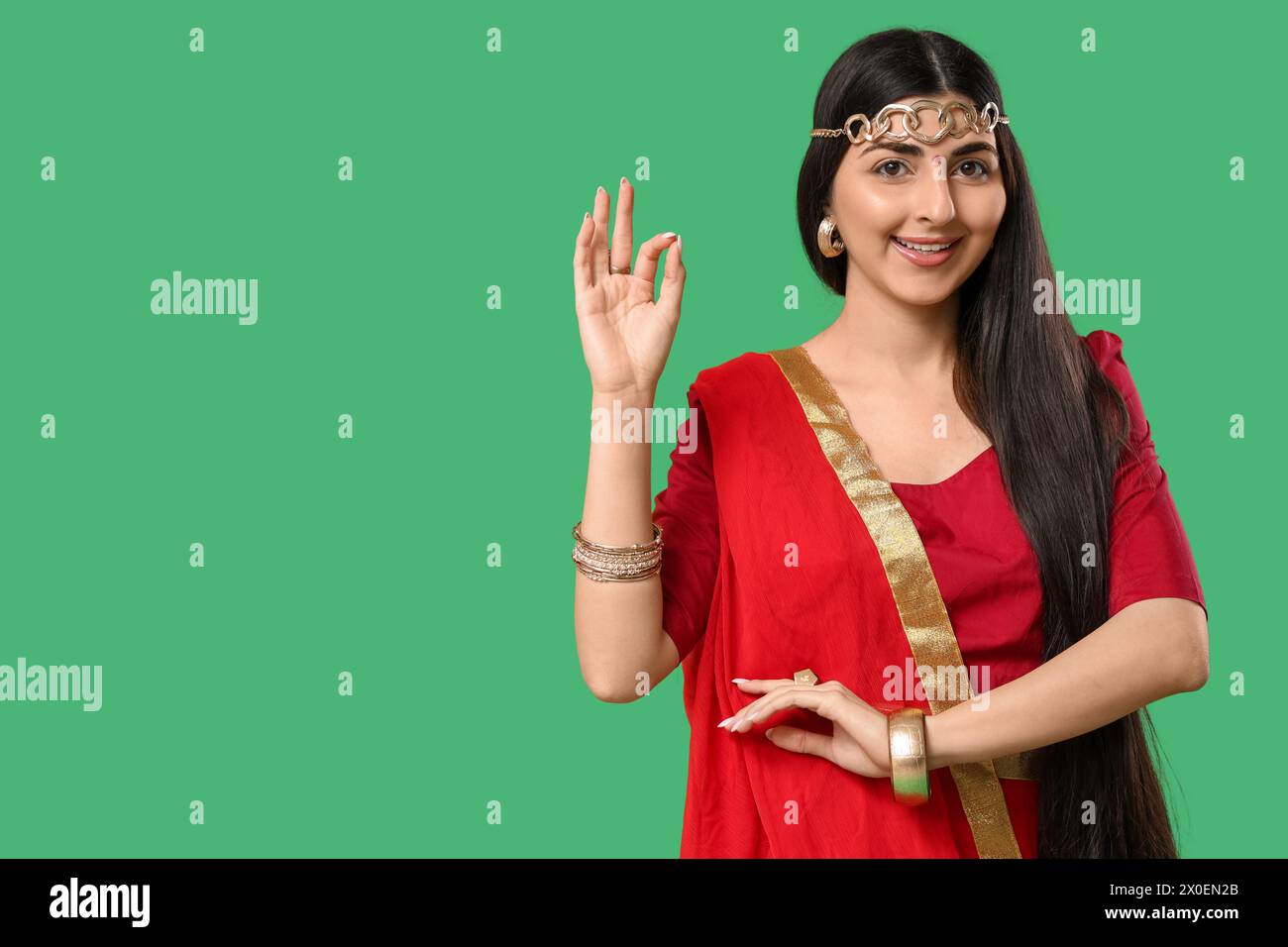 Beautiful Young Happy Indian Woman In Sari Showing Ok Gesture On Green