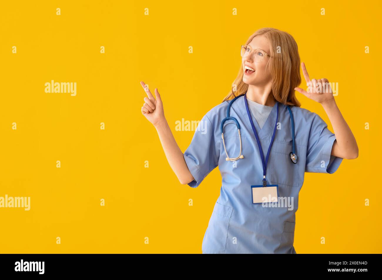 Female happy medical assistant with stethoscope pointing at something ...