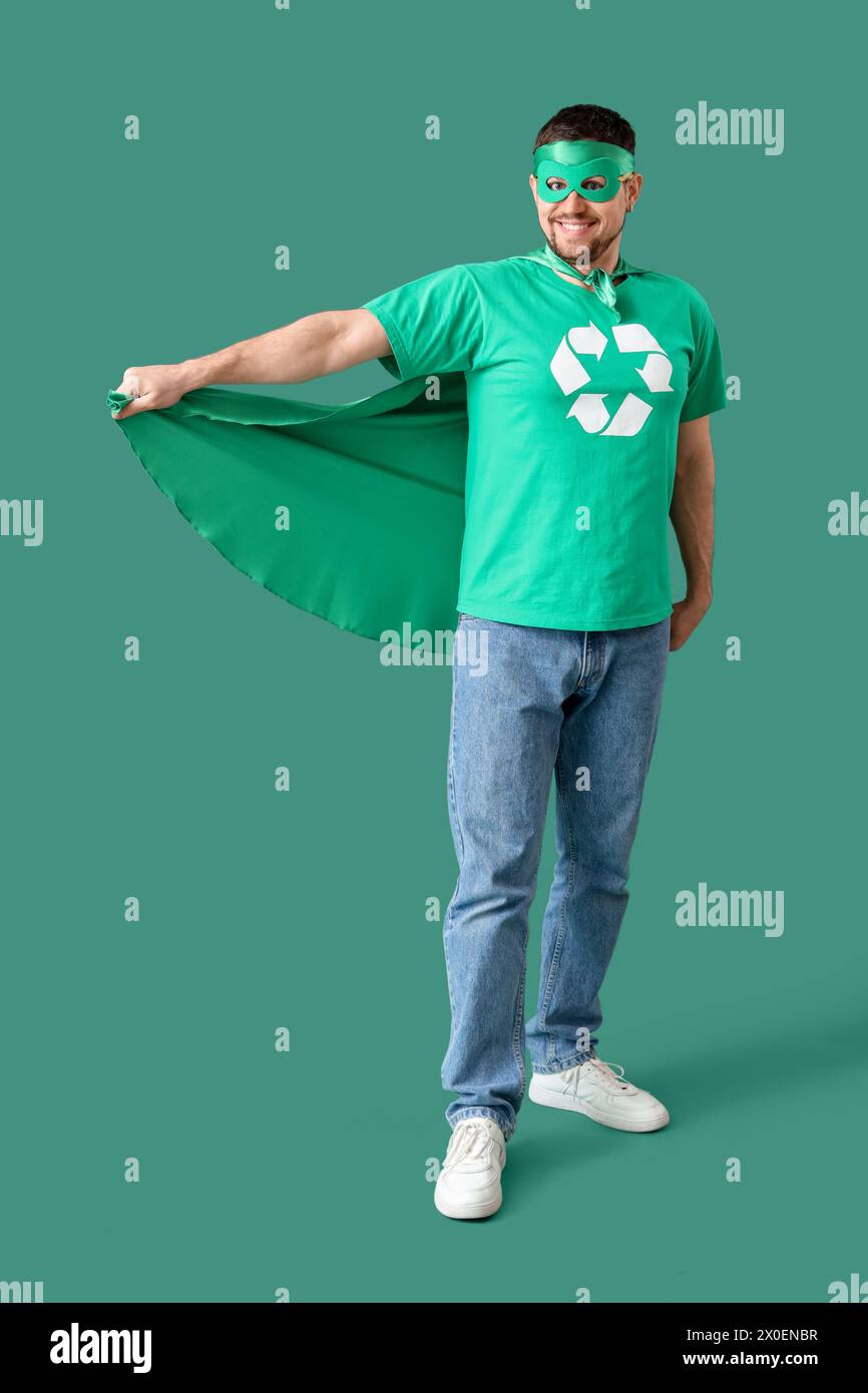 Young man dressed as eco superhero on green background. Ecology concept ...