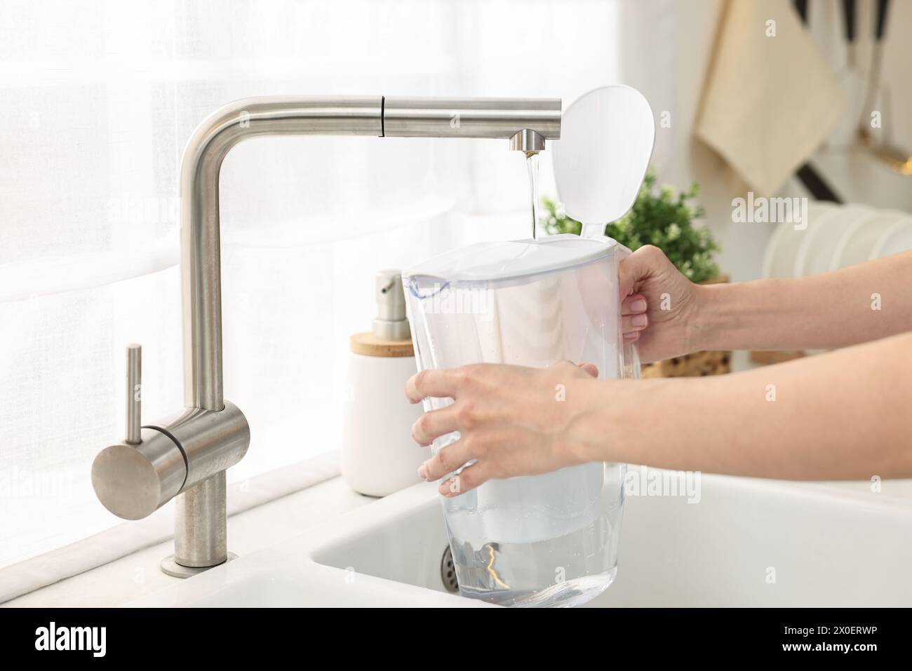 Woman pouring tap water into filter jug in kitchen, closeup Stock Photo ...