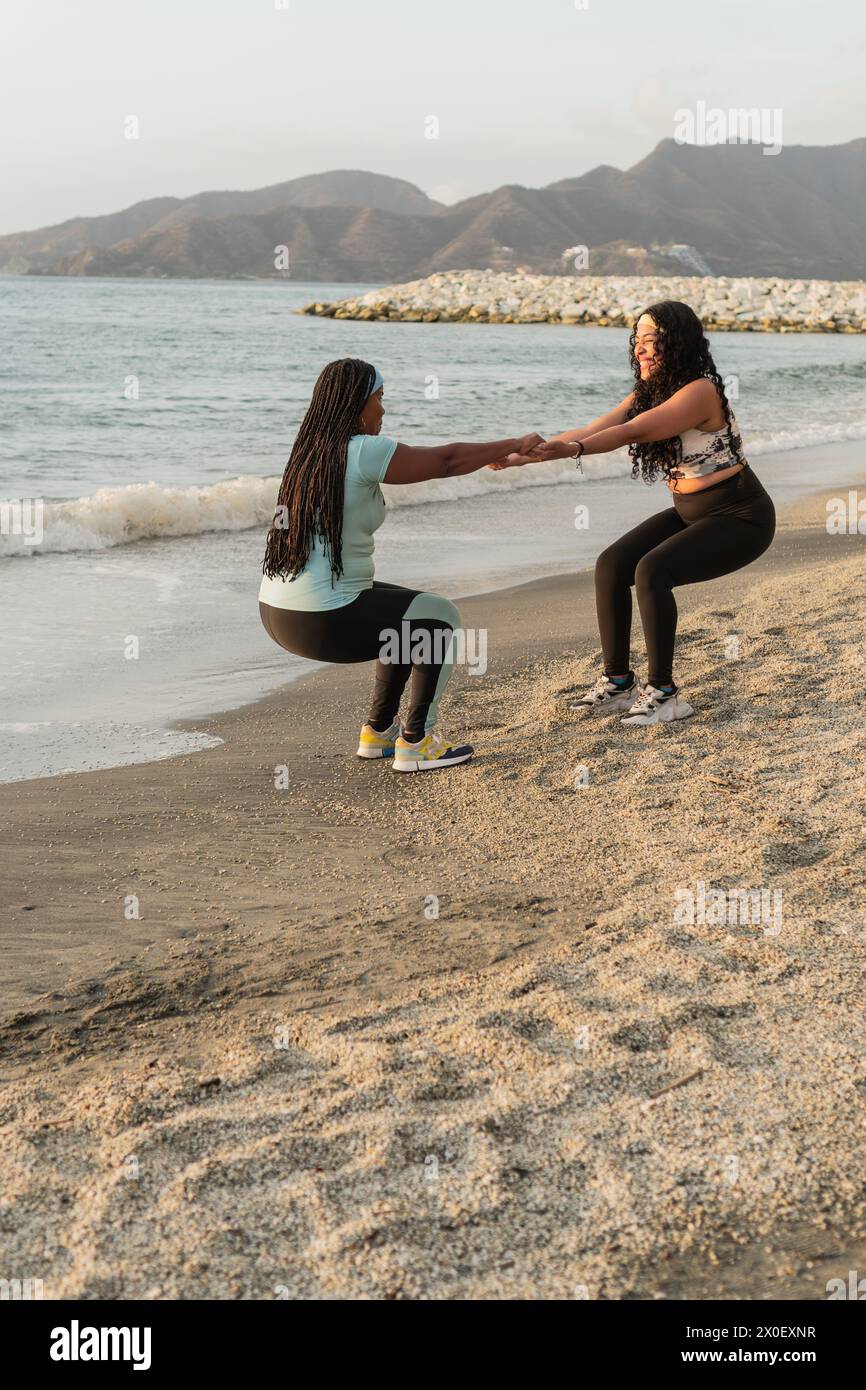 Workout partners engage in squats, assisting each other on a sunlit ...