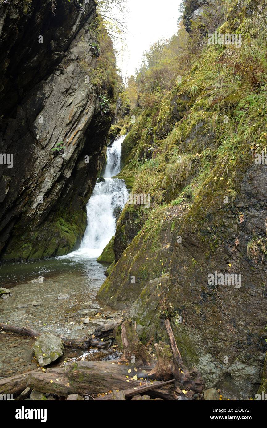A narrow passage of a mountain river bed sandwiched between rocks and flowing down like a rapid ...