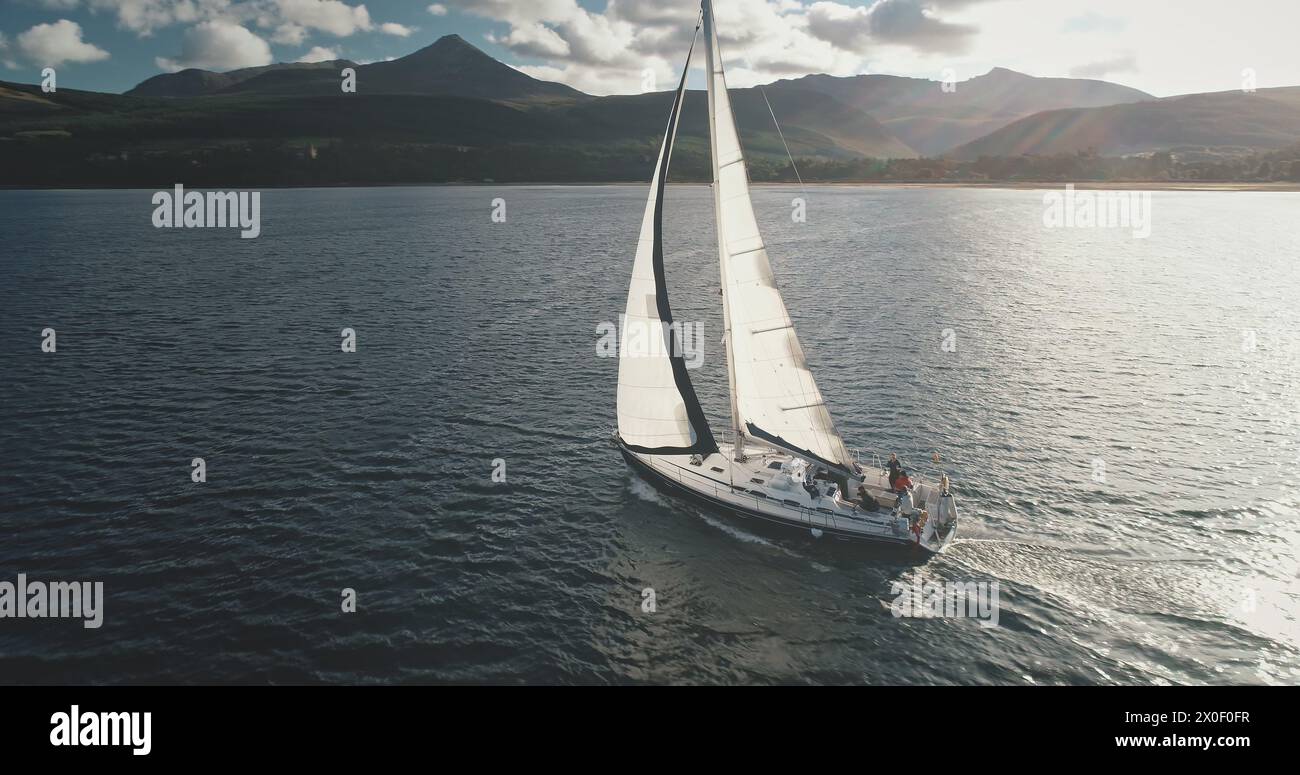 Slow motion yacht sails at mountain island shore aerial. White sailboat ...