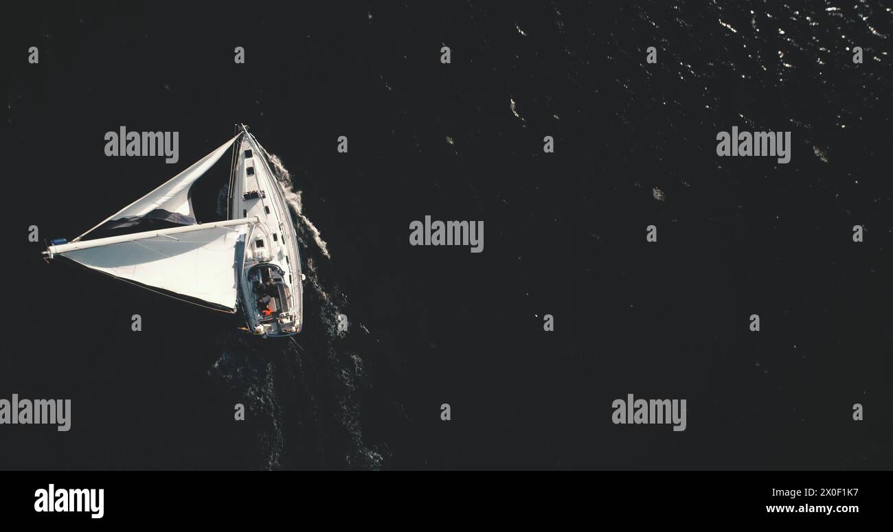 Top down of lone yacht sailing in open sea aerial. Black ocean and ...