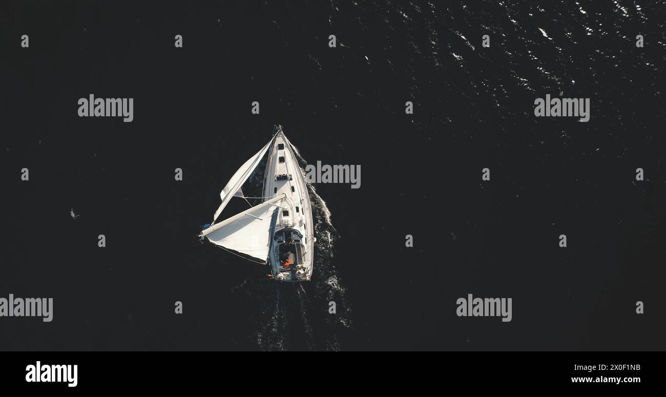 Top down of lone yacht sailing in open sea aerial. Black ocean and ...
