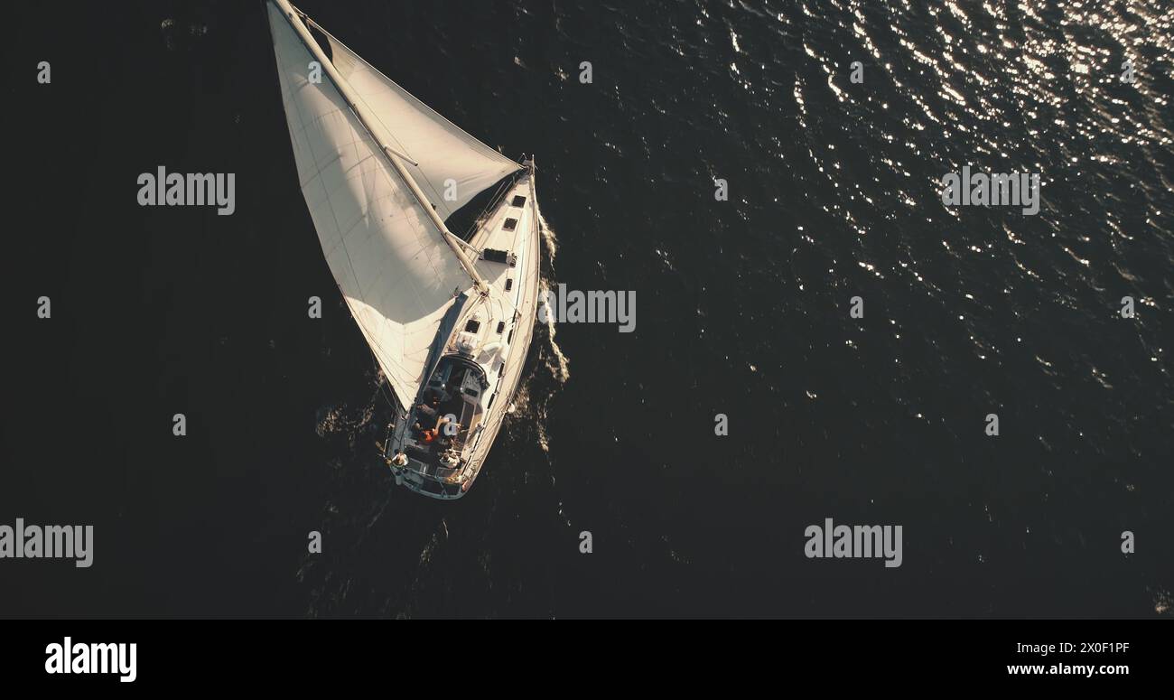 Top down of yacht under white sail at dark open sea aerial. Ocean bay ...