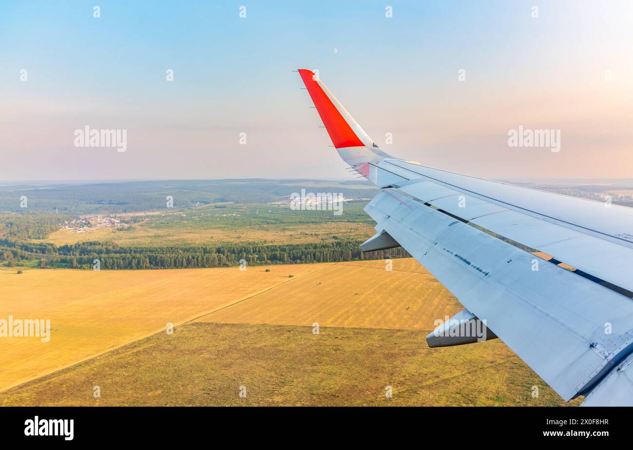 View of airplane wing, blue skies and green land during landing ...