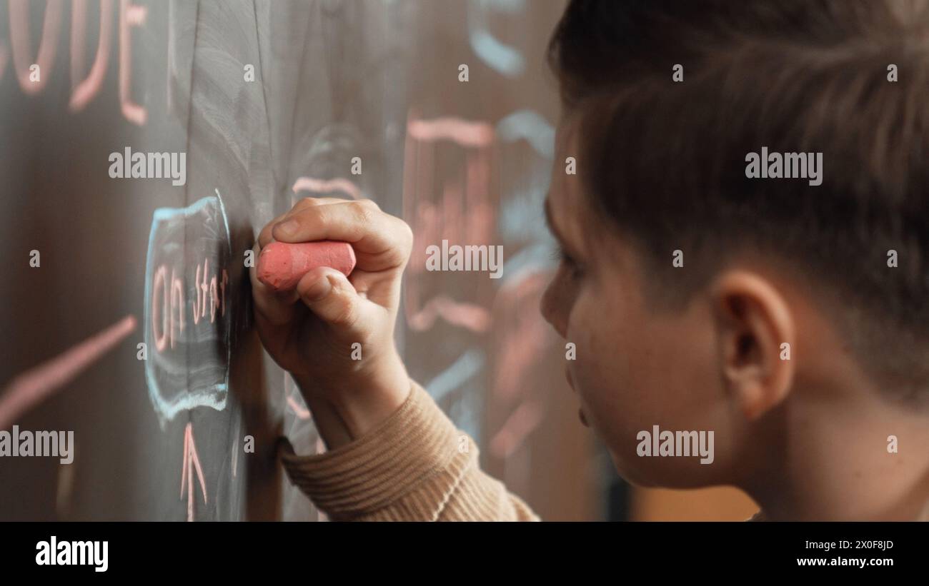 Panorama shot of smart boy writing engineering prompt on blackboard ...
