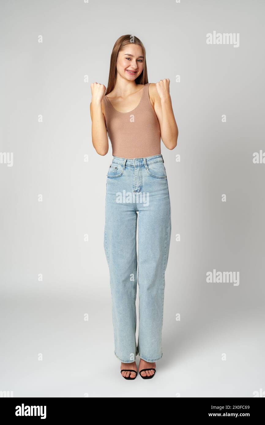 Young woman standing with her arms lifted high above her head ...