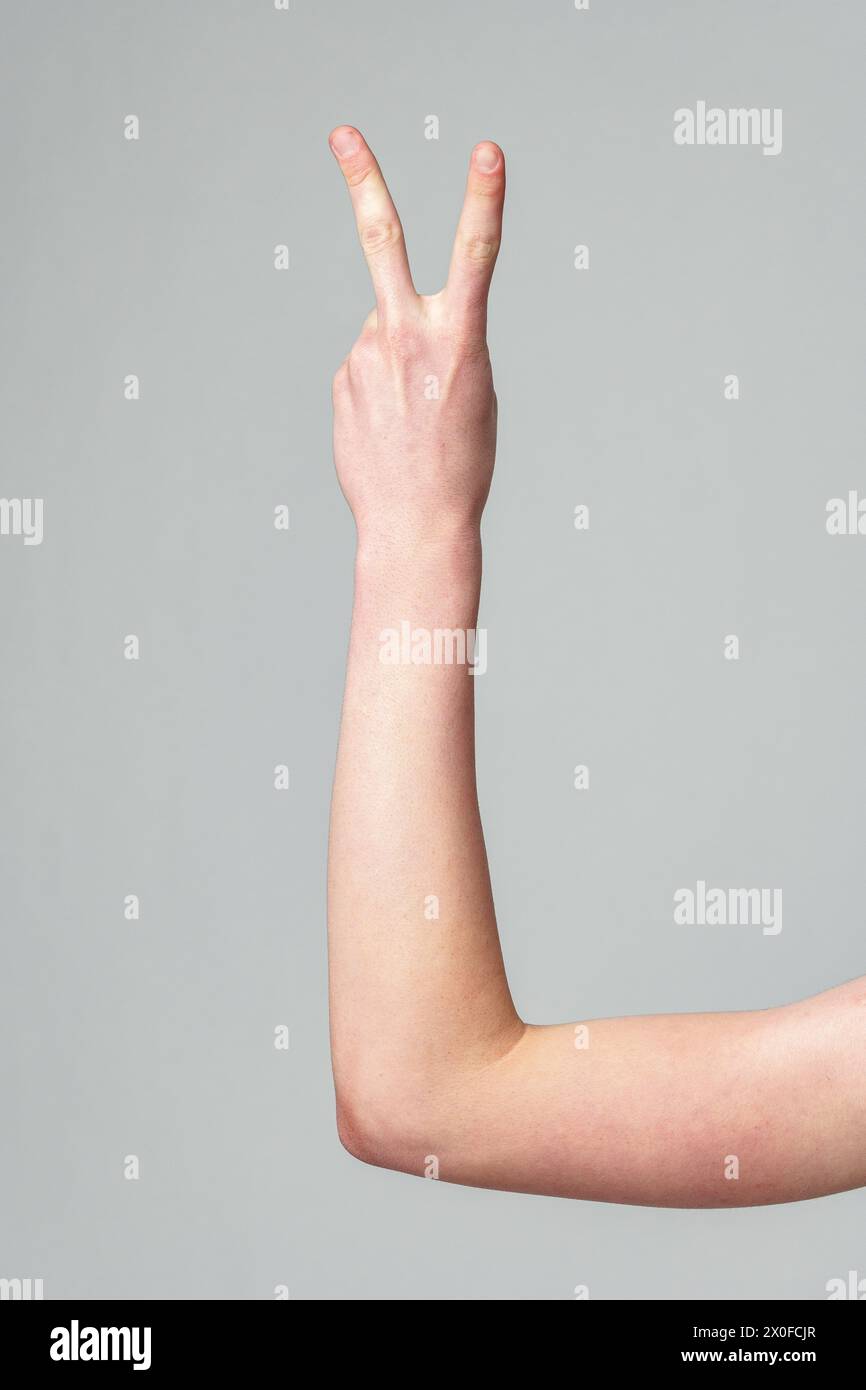 Raised Hand Making Peace Sign Against Plain Gray Background Stock Photo ...