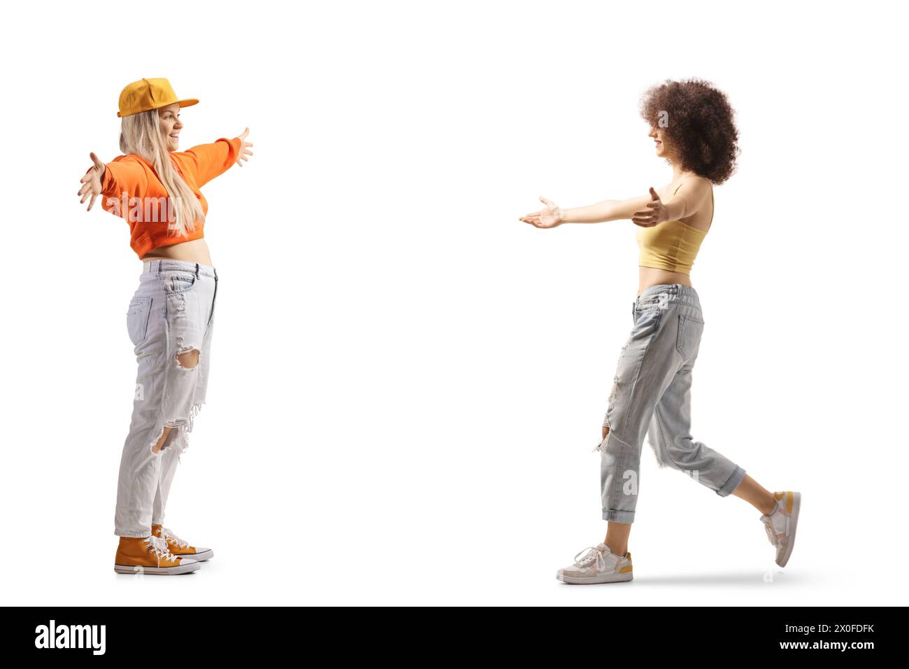 Full length profile shot of young female friends meeting each other ...