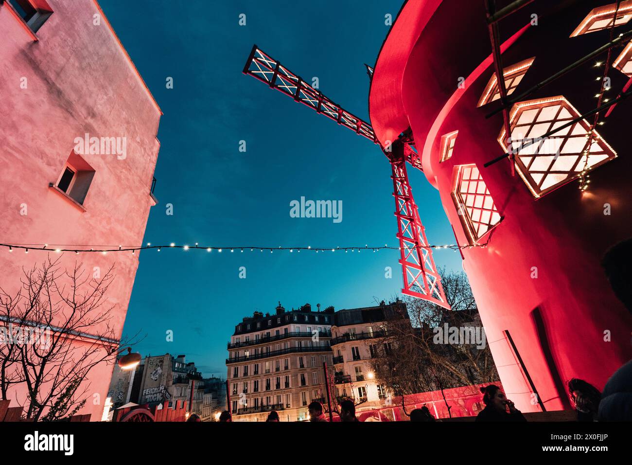 Moulin Rouge at night with lights during French sunset. Spinning moulin ...