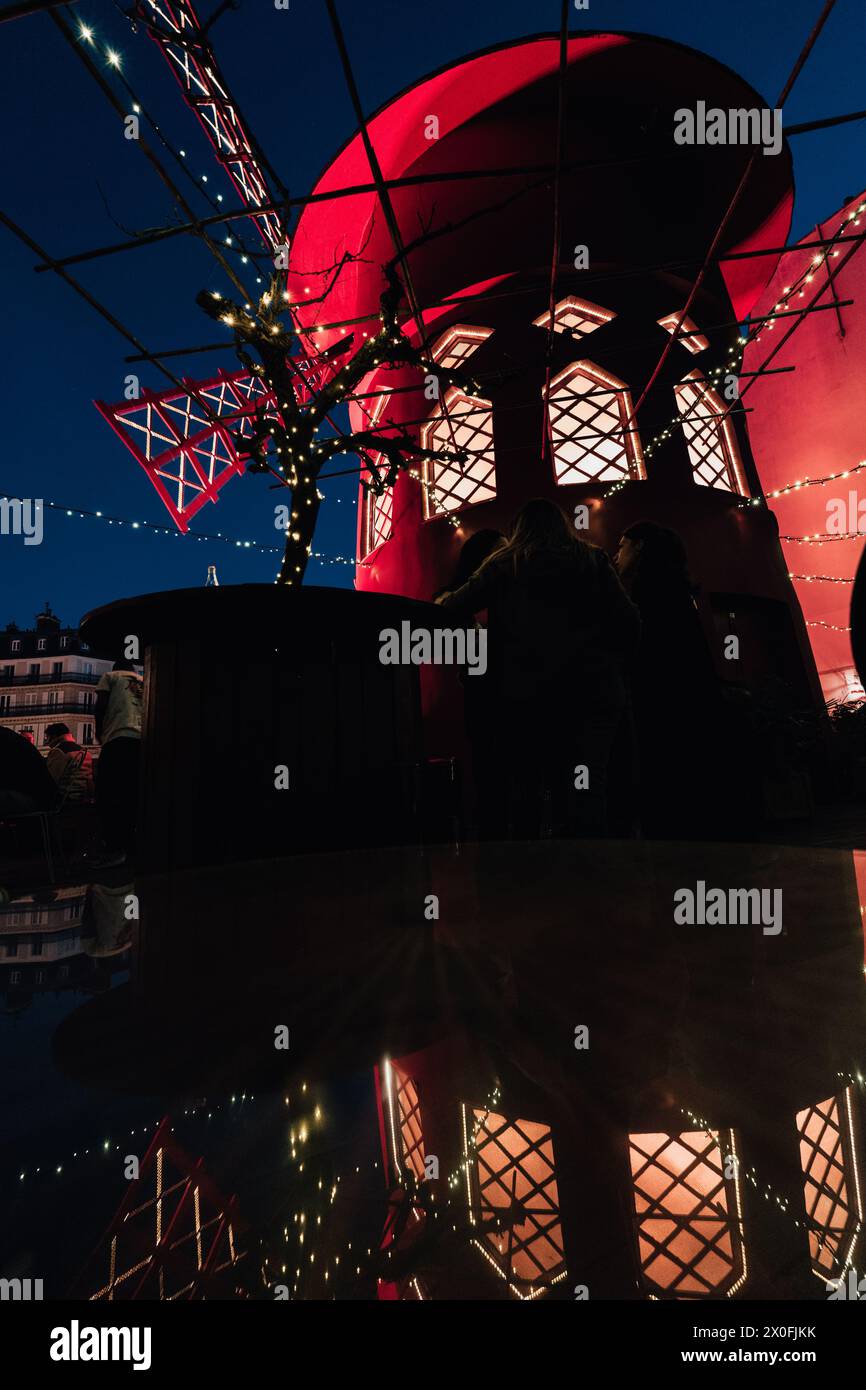 Moulin Rouge at night with lights during French sunset. Spinning moulin ...
