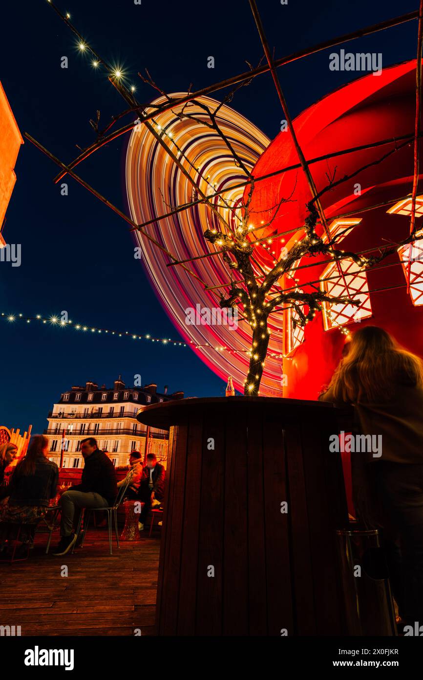Moulin Rouge at night with lights during French sunset. Spinning moulin ...