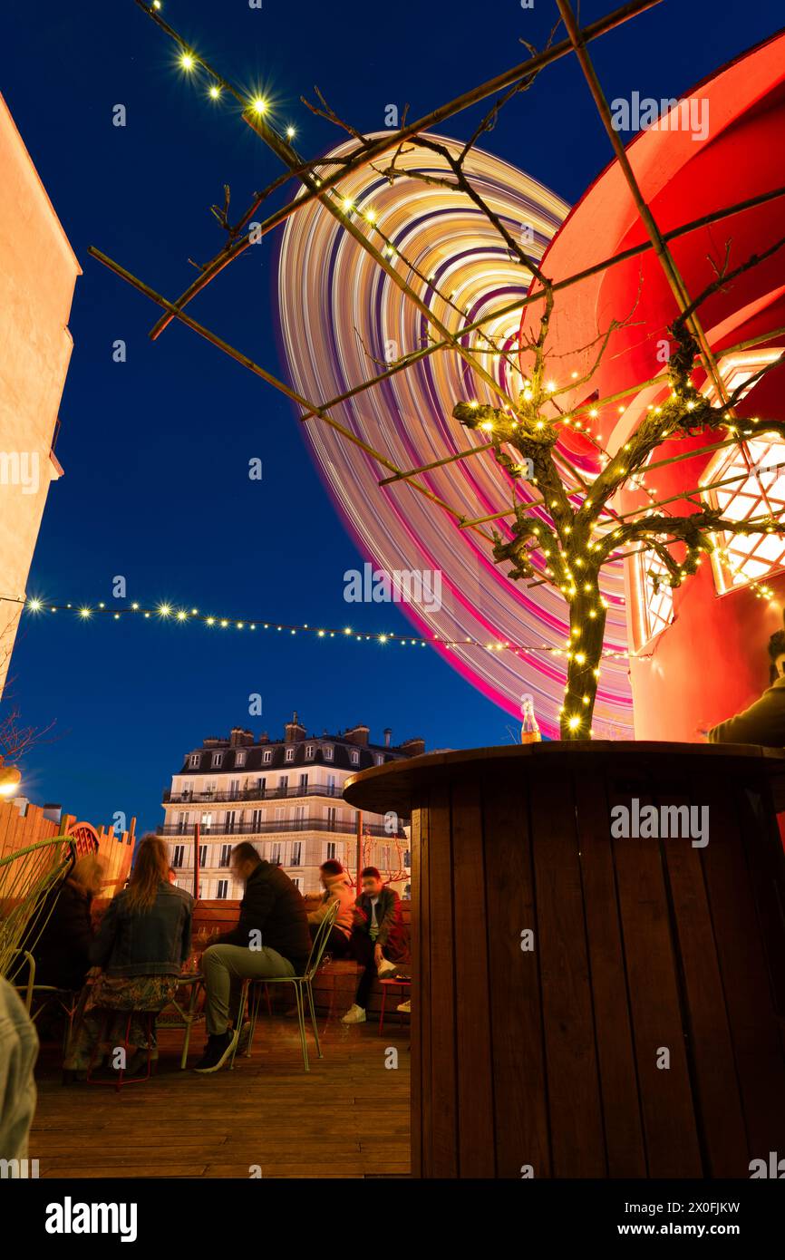 Moulin Rouge at night with lights during French sunset. Spinning moulin ...