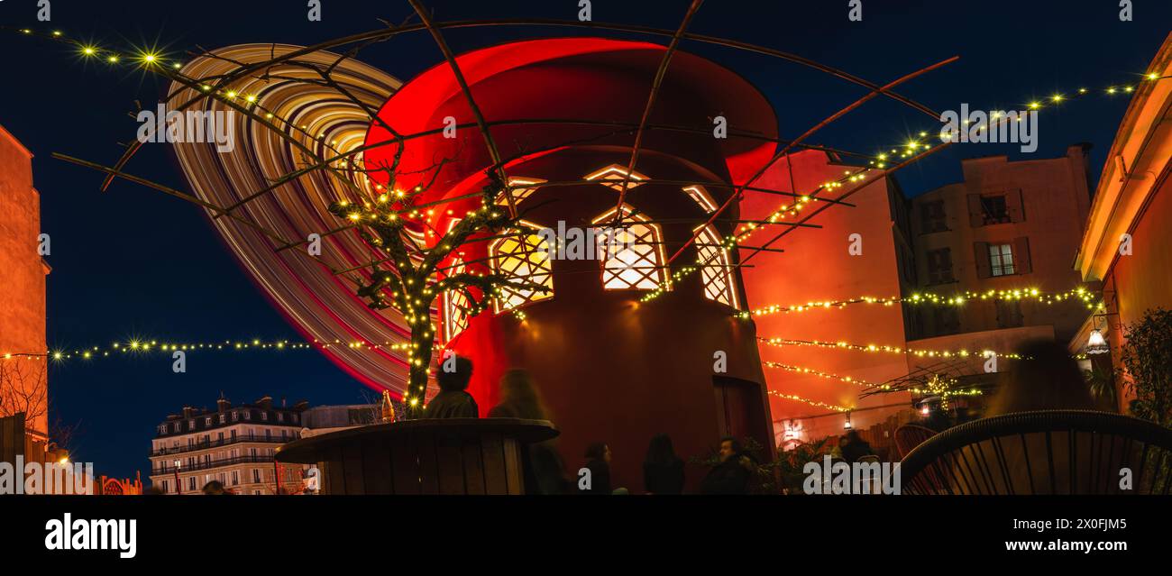 Moulin Rouge at night with lights during French sunset. Spinning moulin ...