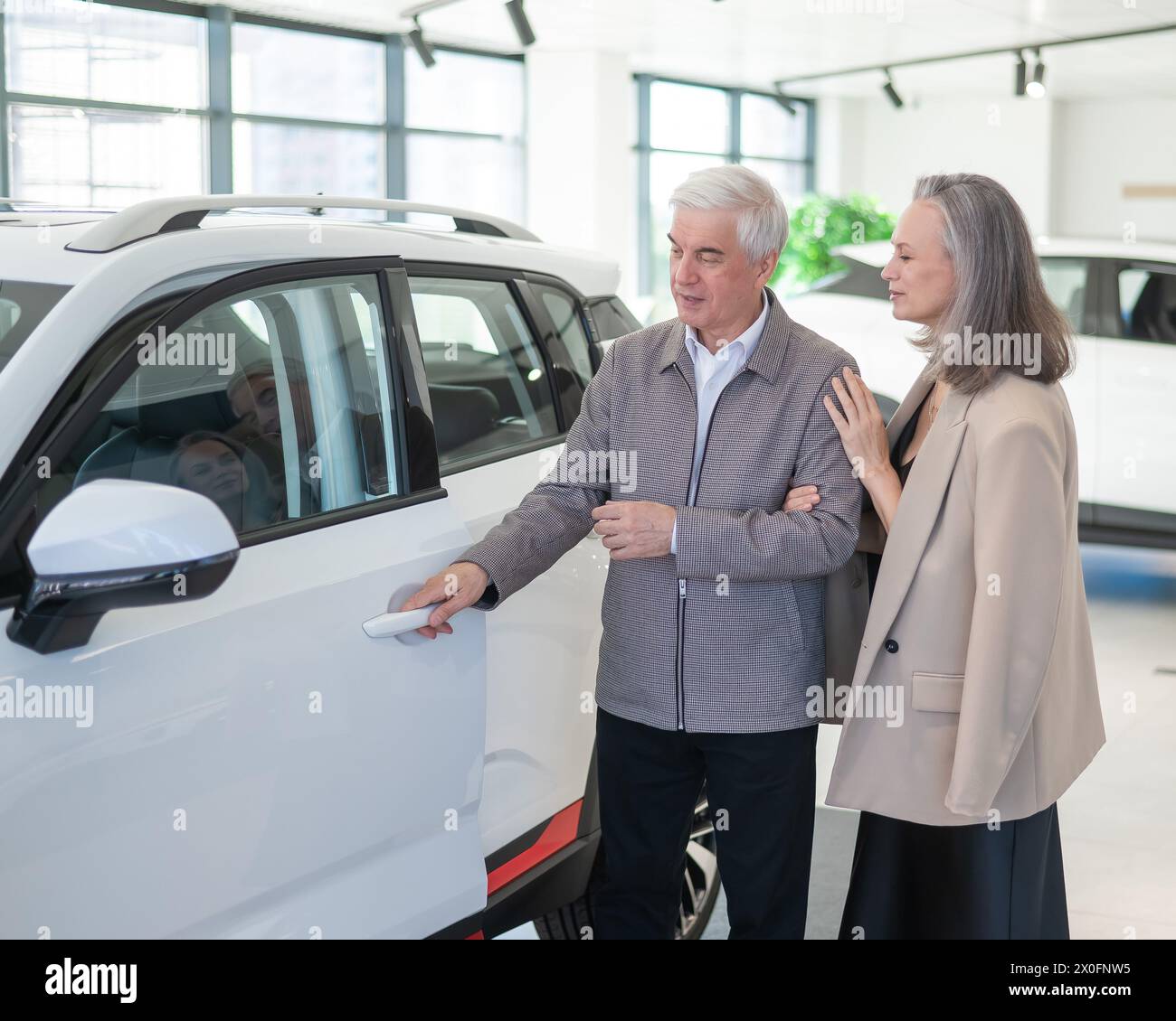 An elderly Caucasian couple chooses a new car at a car dealership Stock ...