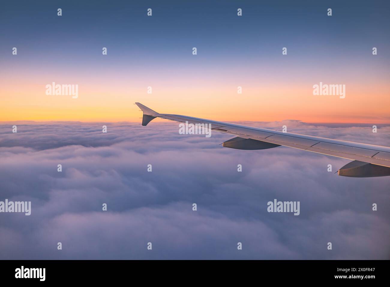 Airplane flying over color sky clouds during scenic sunset or sunrise ...