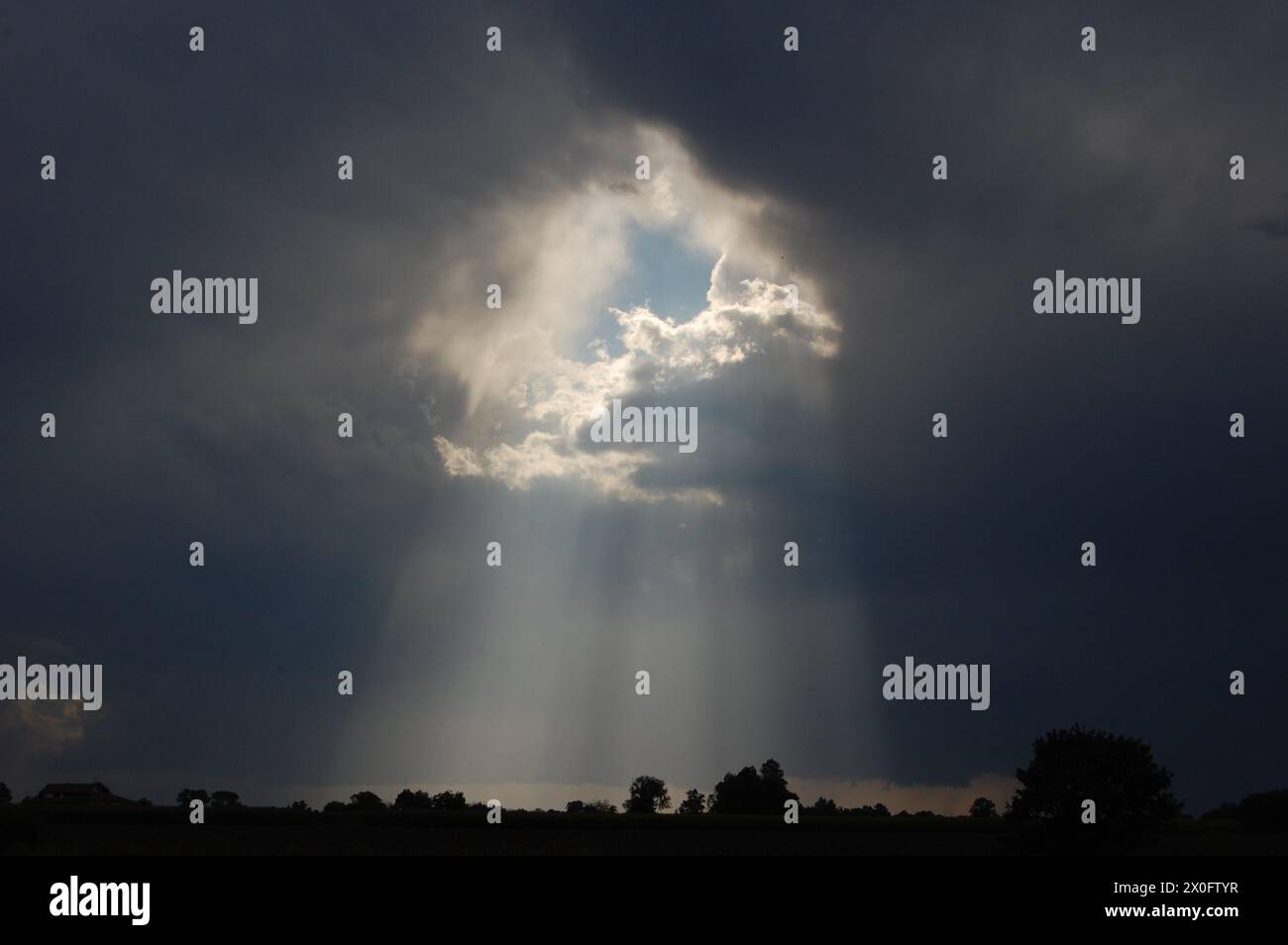 opening in the clouds in a gray sky with sun rays towards the earth ...