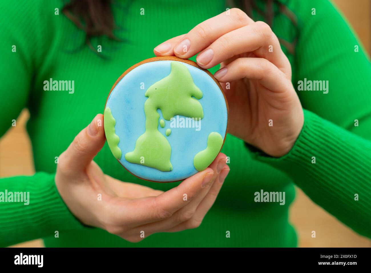 Earth Day concept. Gingerbread in the shape of a planet in the hands of ...