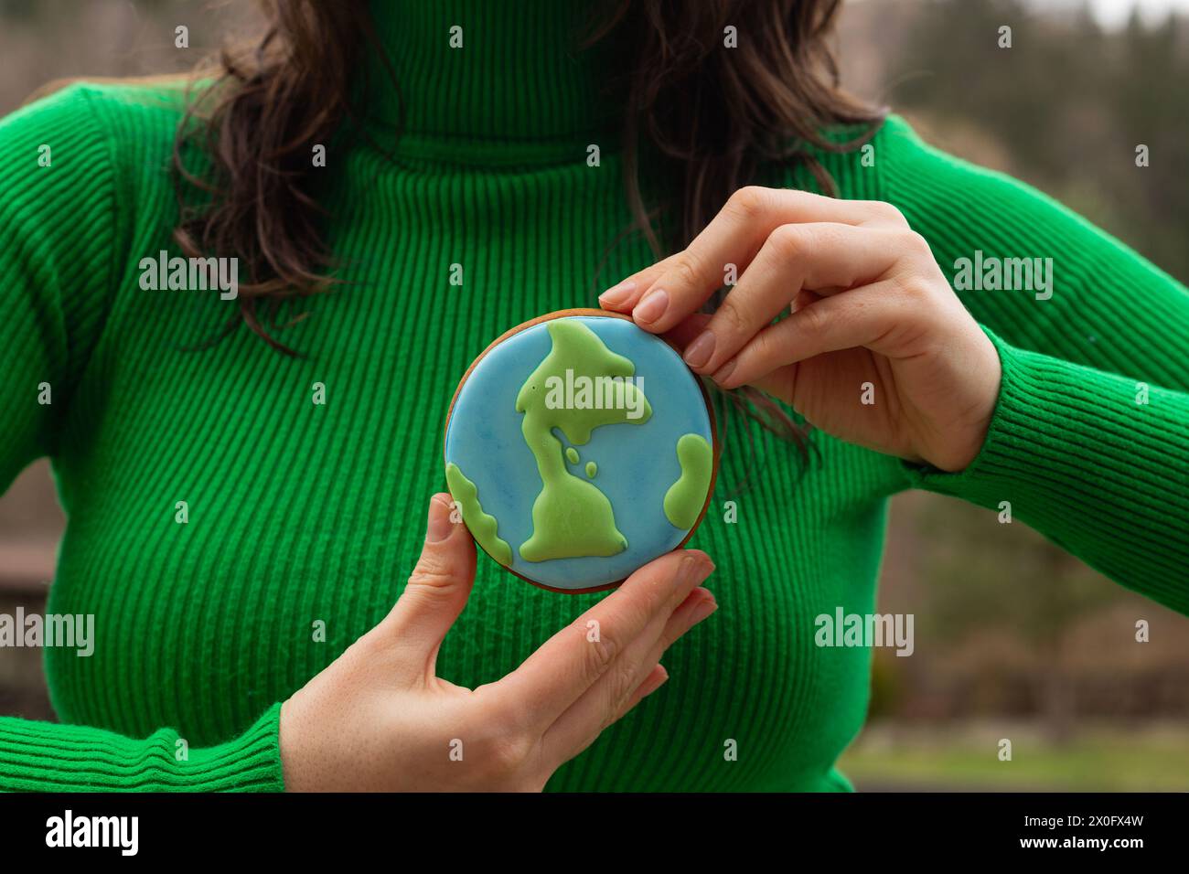 Earth Day concept. Gingerbread in the shape of a planet in the hands of ...