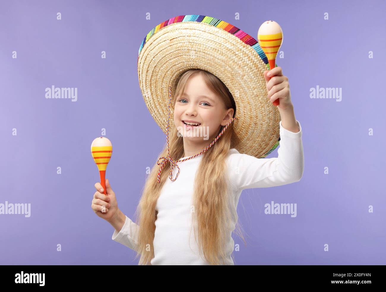 Cute girl in Mexican sombrero hat dancing with maracas on purple ...