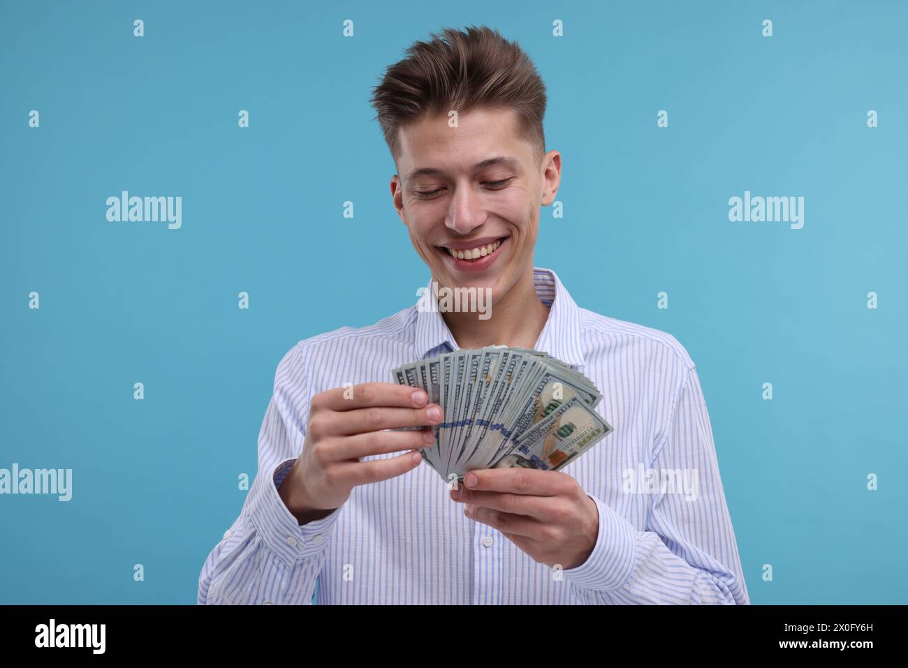 Happy man counting dollar banknotes on light blue background Stock ...
