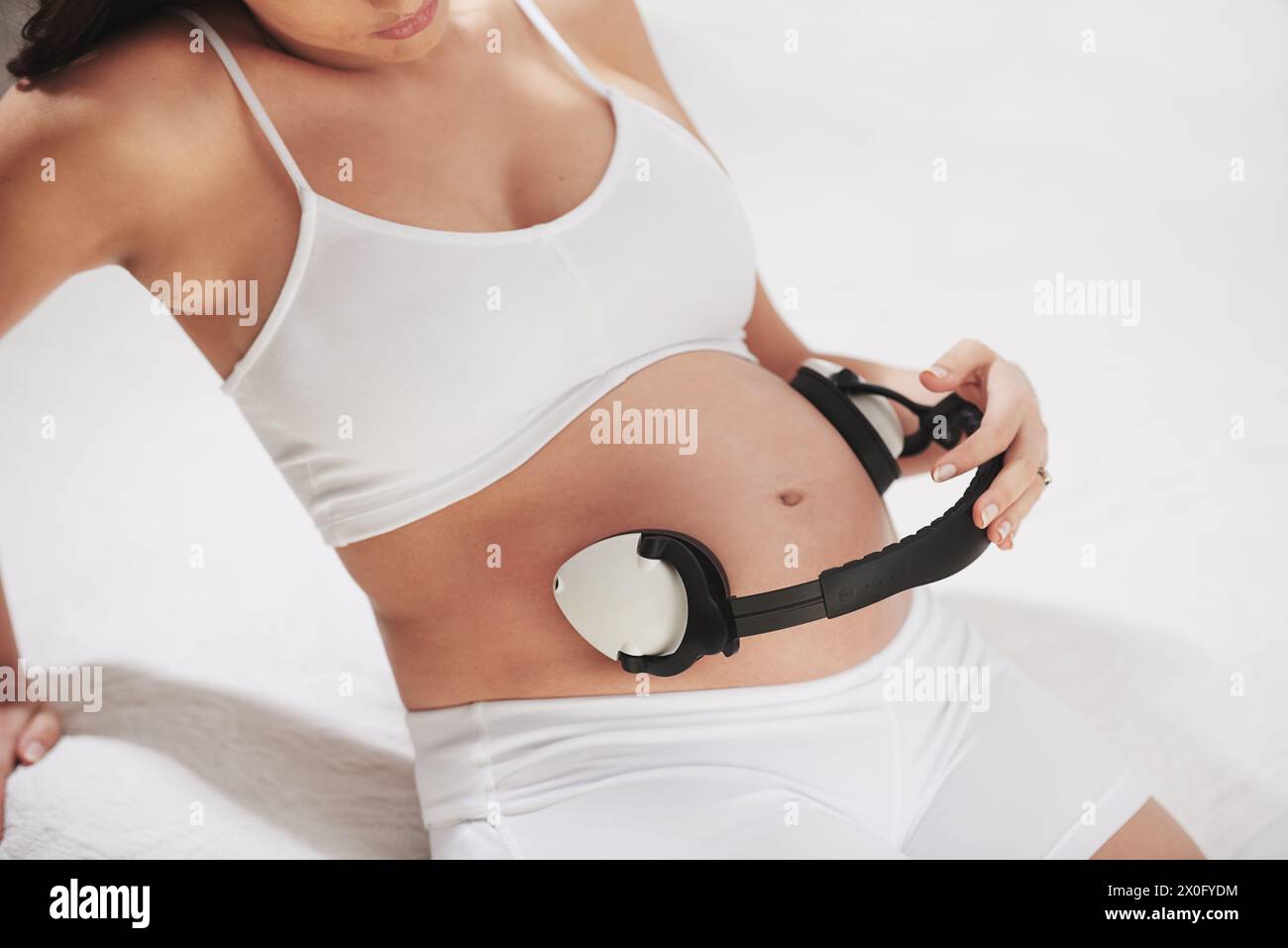 Pregnant, stomach and listening to music with headphones so baby relax to sound in womb for ...